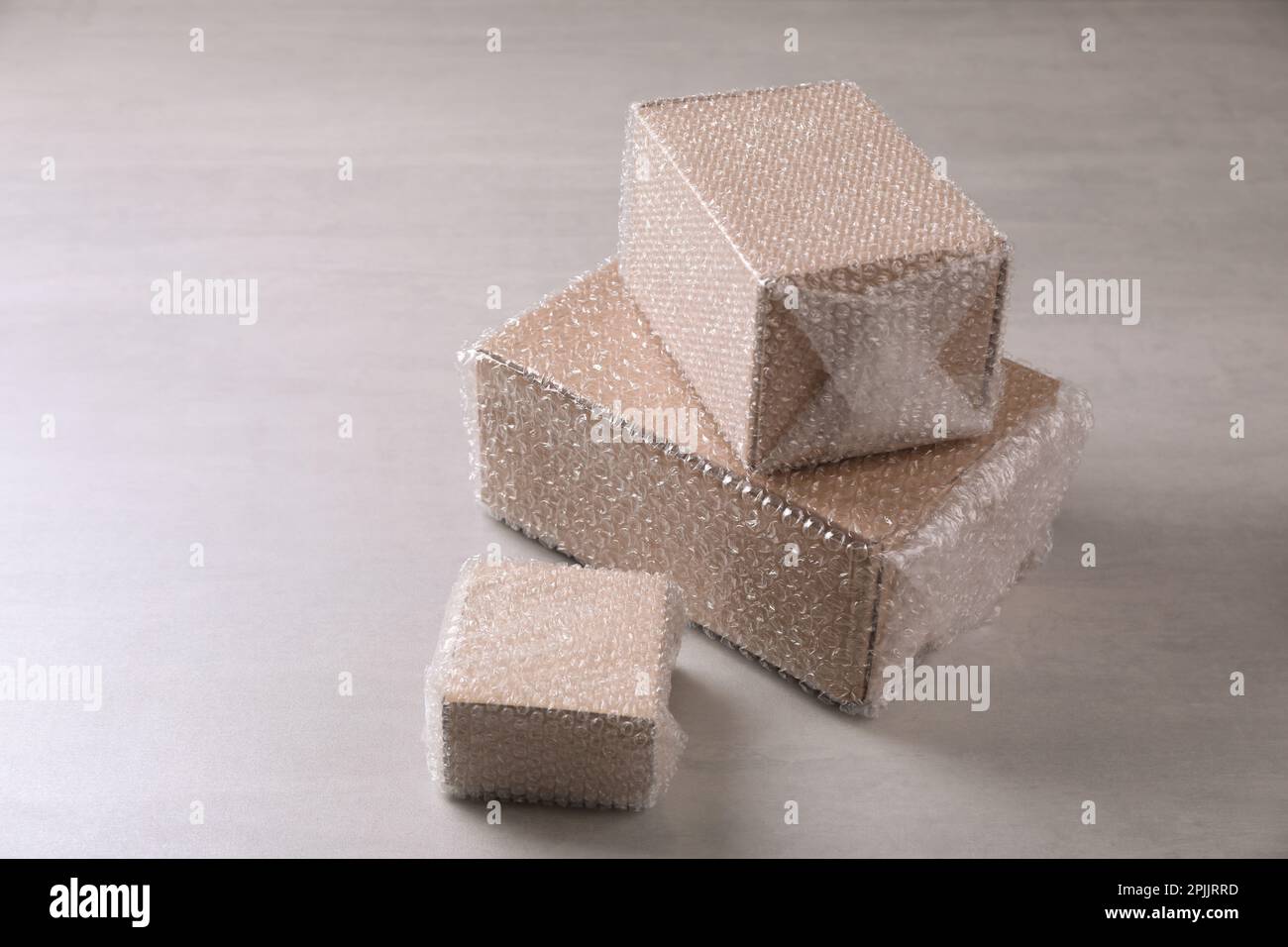 Cardboard boxes covered with bubble wrap on light grey table Stock ...