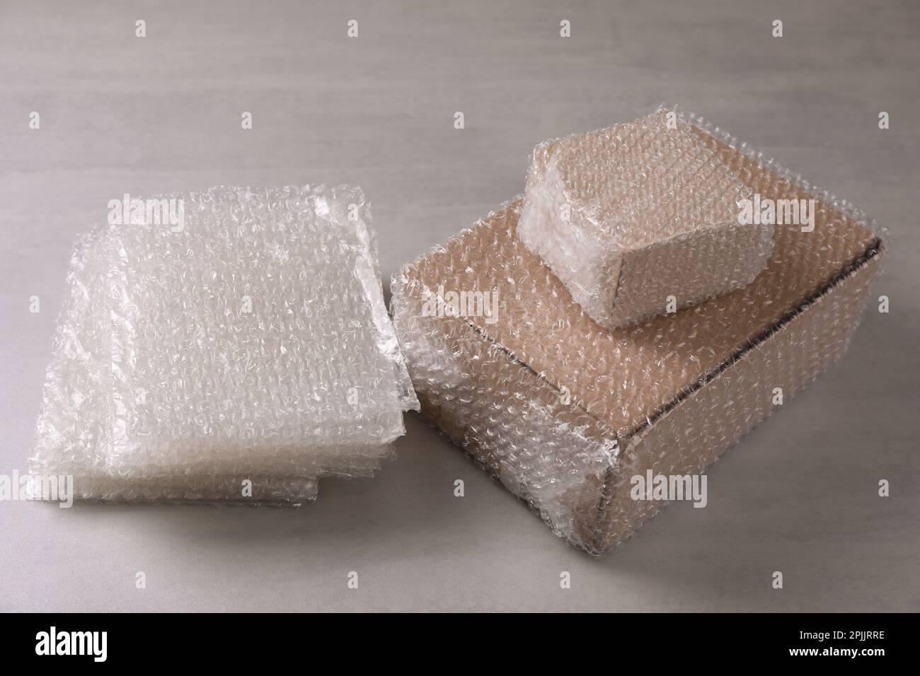Cardboard boxes and bubble wrap on light grey table Stock Photo - Alamy