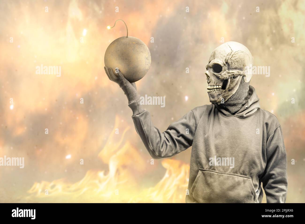 A man wearing a mask standing while holding a ball bomb with a fire ...
