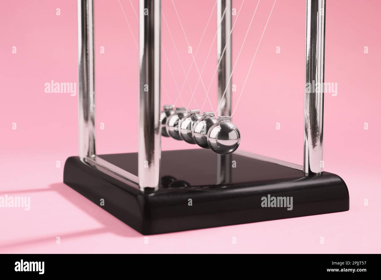 Newton's cradle on pink background, closeup. Physics law of energy ...