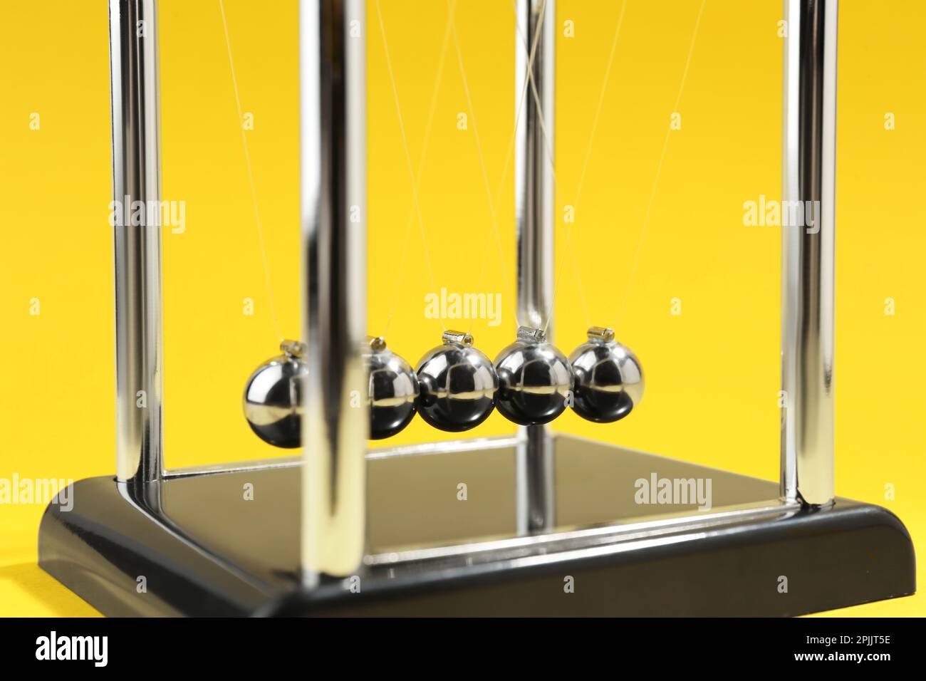 Newton's cradle on yellow background, closeup. Physics law of energy ...