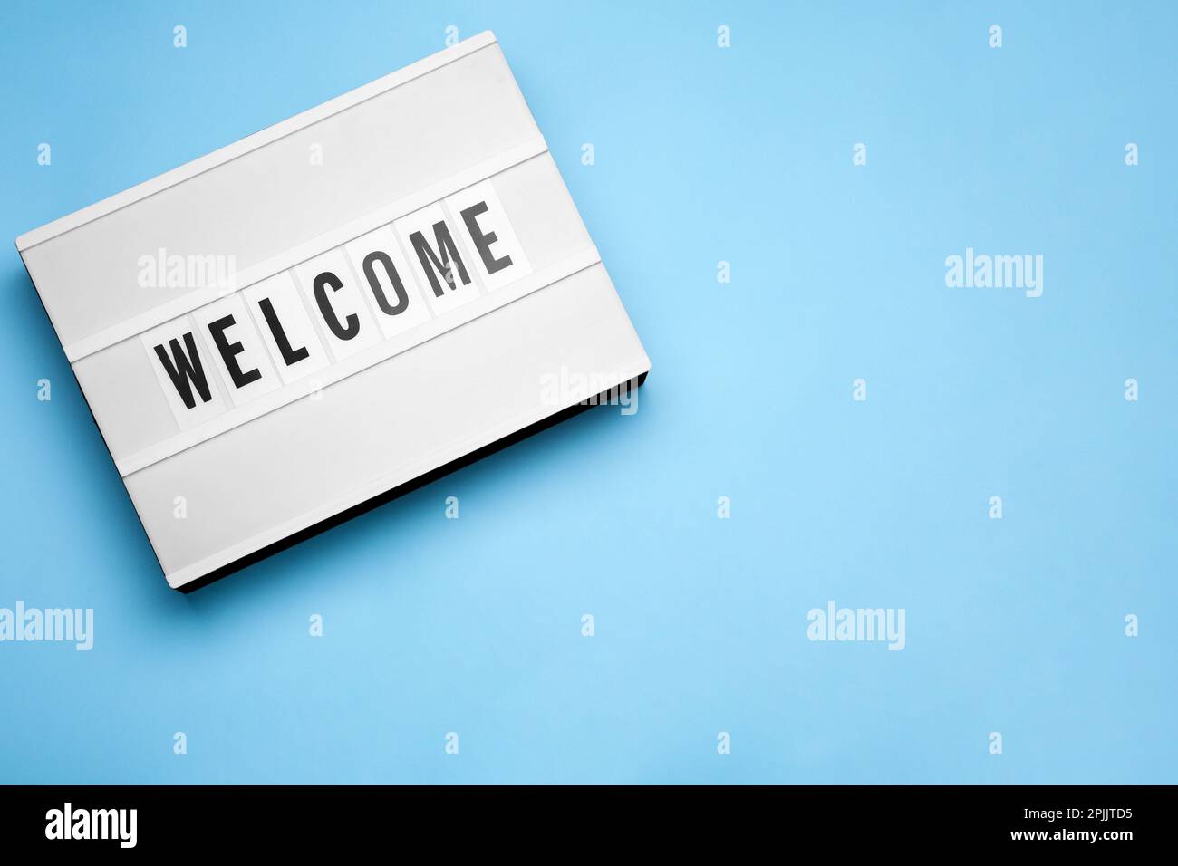 Lightbox with word Welcome on light blue background, top view. Space ...