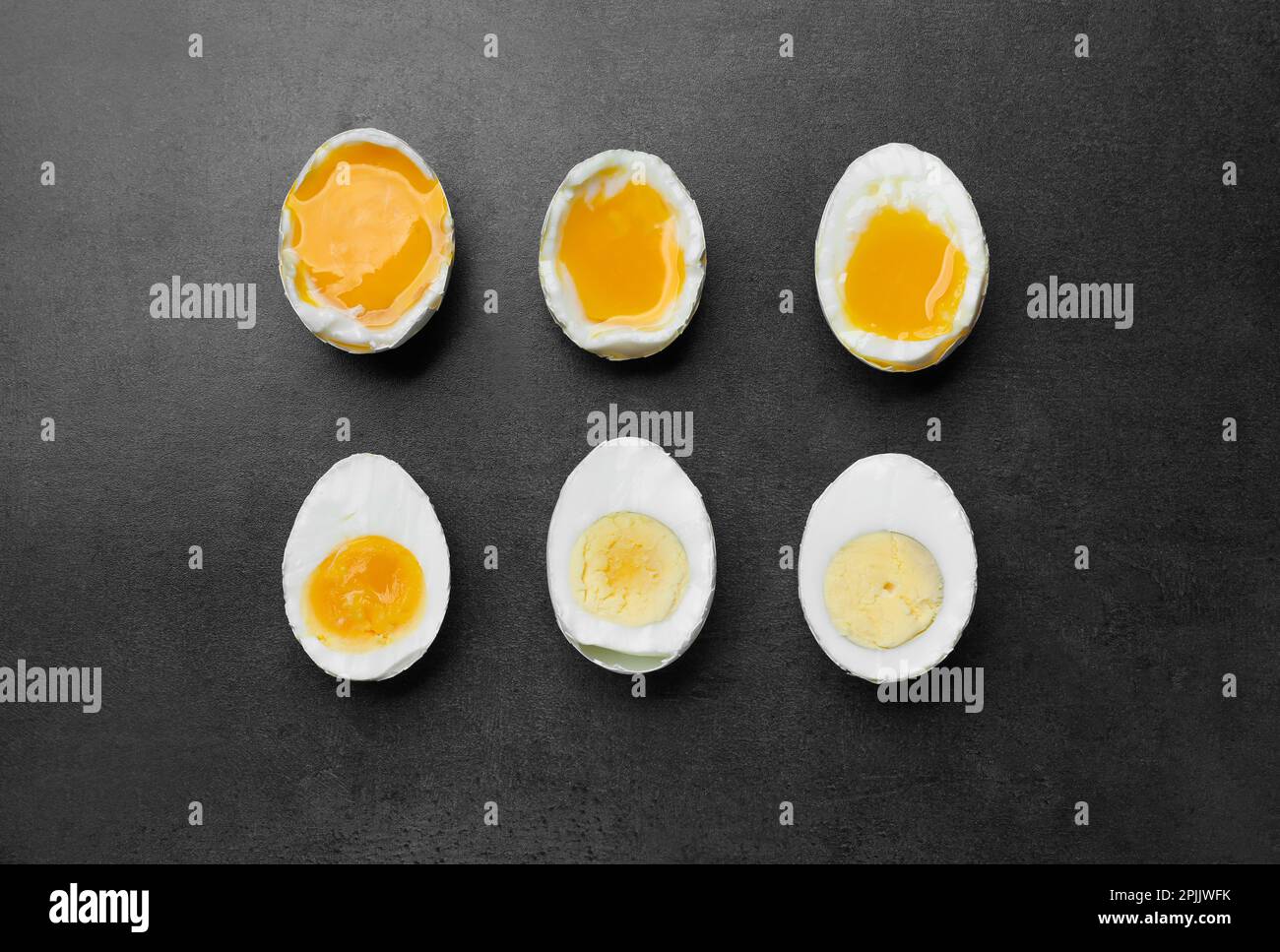 Different readiness stages of boiled chicken eggs on dark grey table ...