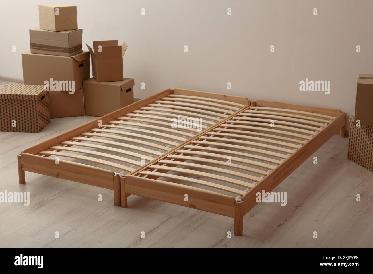 Wooden bed frame and cardboard boxes on floor in room Stock Photo - Alamy