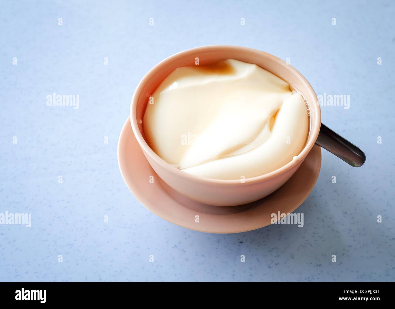 Tau foo fah (Soy bean pudding) in a bowl on top of a table. Copy space ...