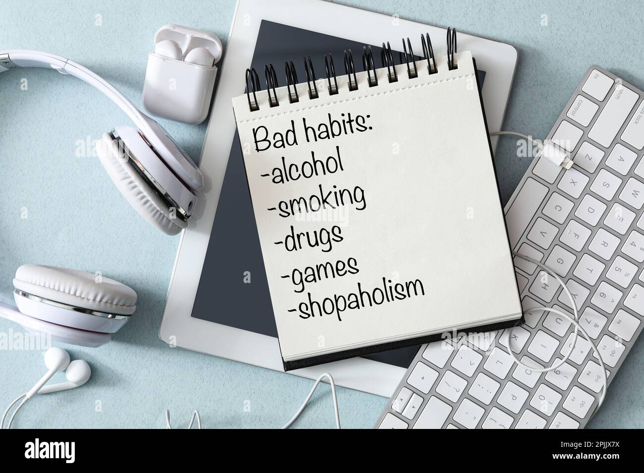 Notebook with list of bad habits, different earphones, tablet and ...