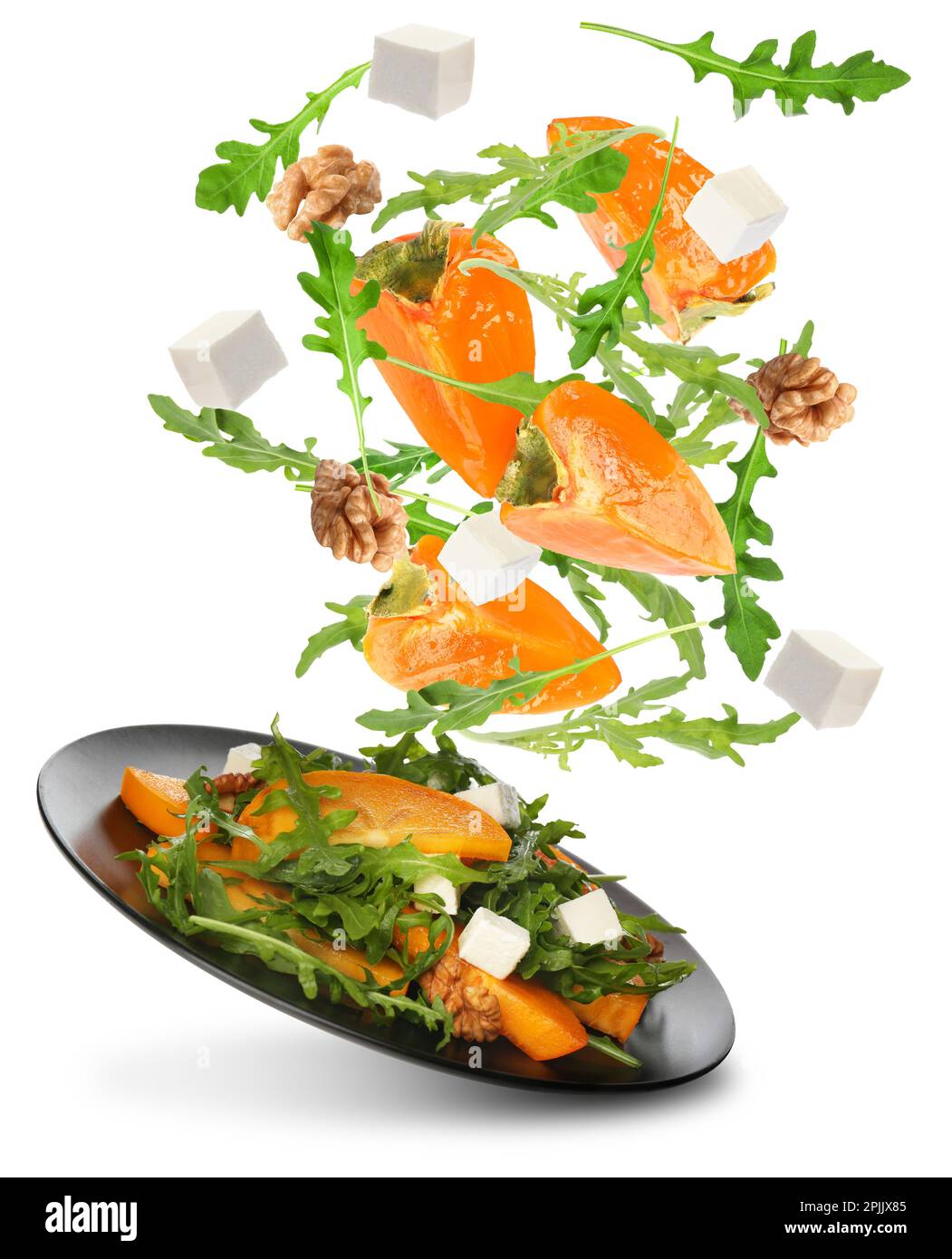 Tasty ingredients for persimmon salad falling into plate on white ...