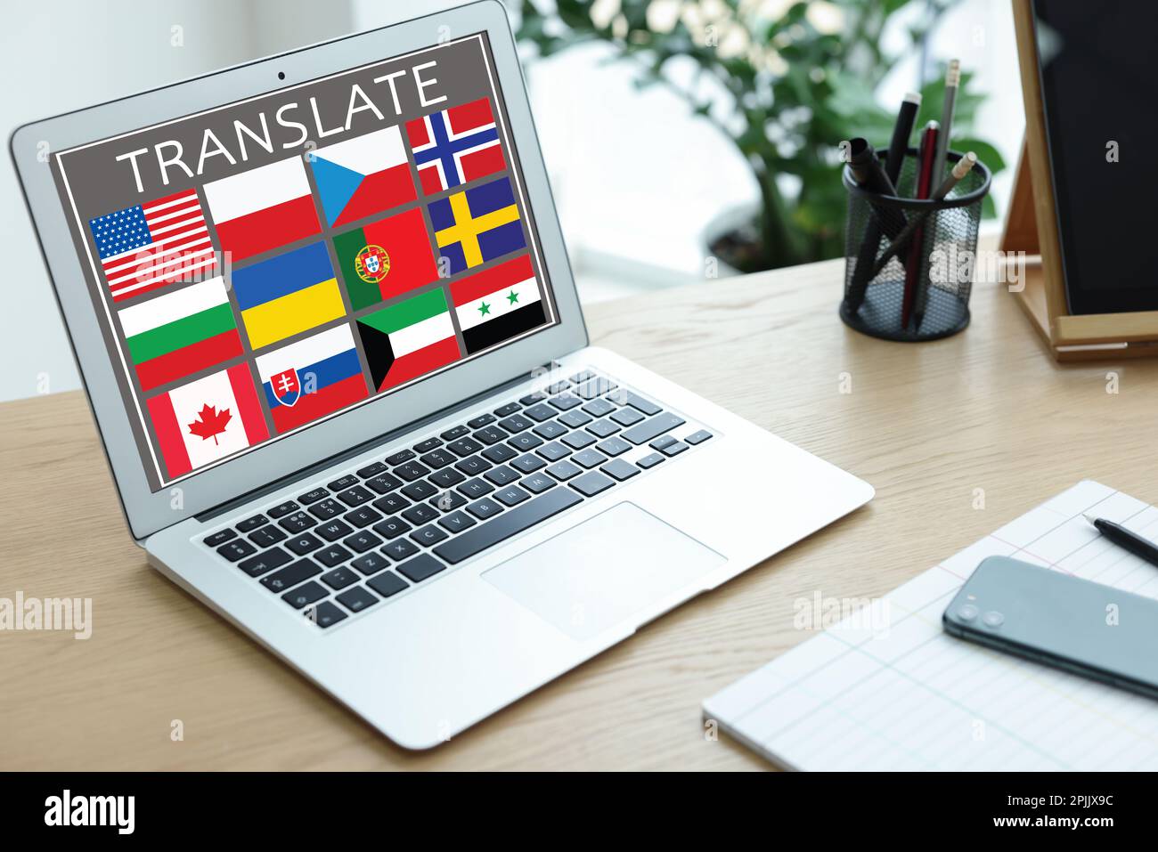 Workplace with laptop and images of different flags on screen, phone ...