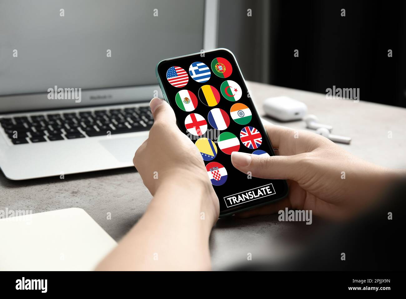 Translator using smartphone with images of different flags on screen at ...