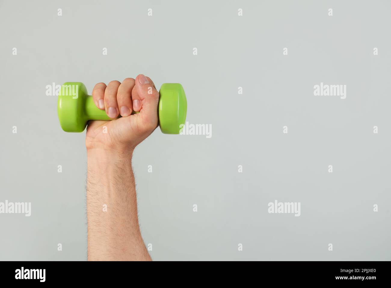 Man holding dumbbell on grey background, closeup. Space for text Stock ...