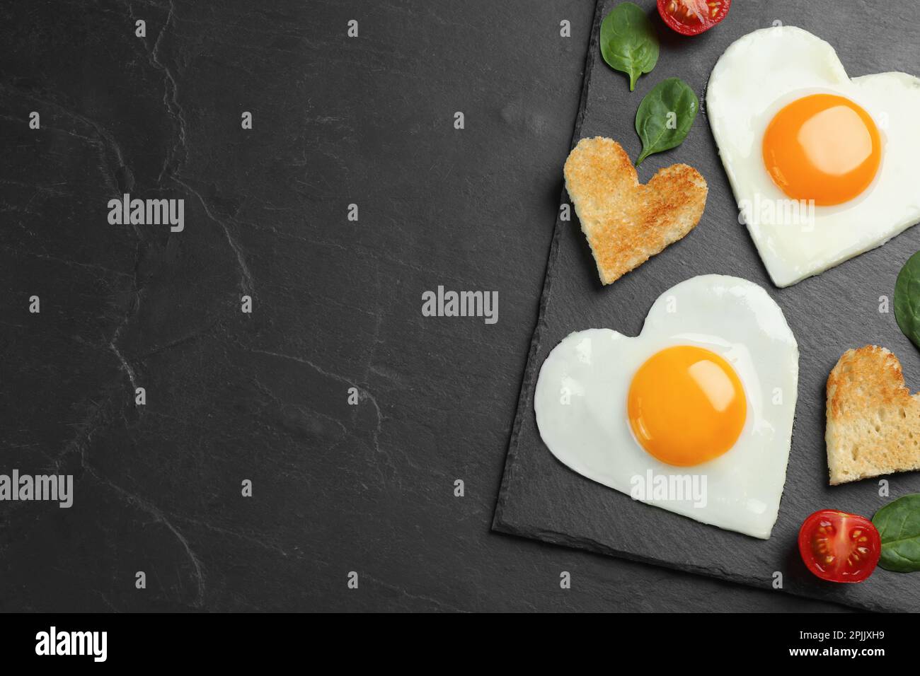 Heart shaped fried eggs and toasts on black table, top view. Space for text Stock Photo - Alamy