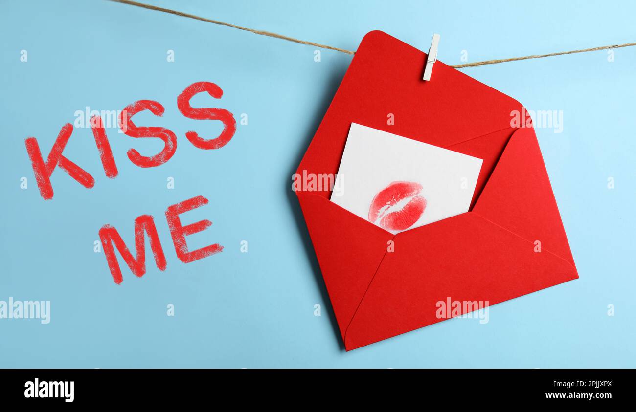 Card with lip print in red envelope and phrase Kiss Me on light blue ...