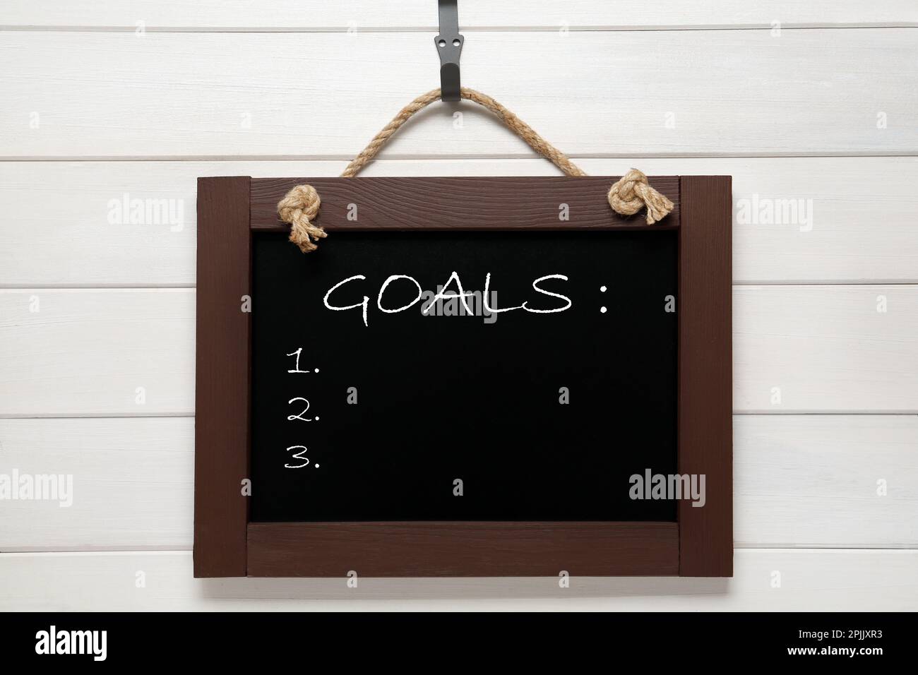 Blackboard with word GOALS and empty checklist on hanging on white ...