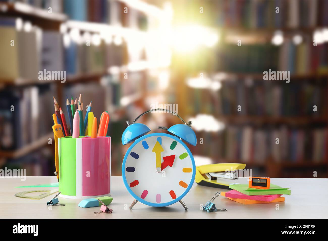 Light blue alarm clock and different stationery on white table in ...