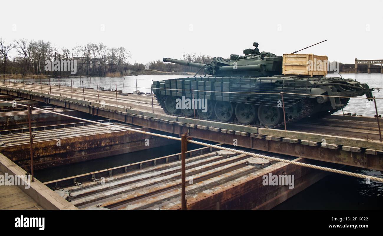 Ukrainian T-72B tank crossing a pontoon bridge rising to the front line ...