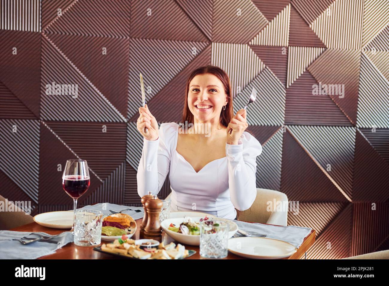 Beautiful woman sits by table. Indoors of new modern luxury restaurant ...
