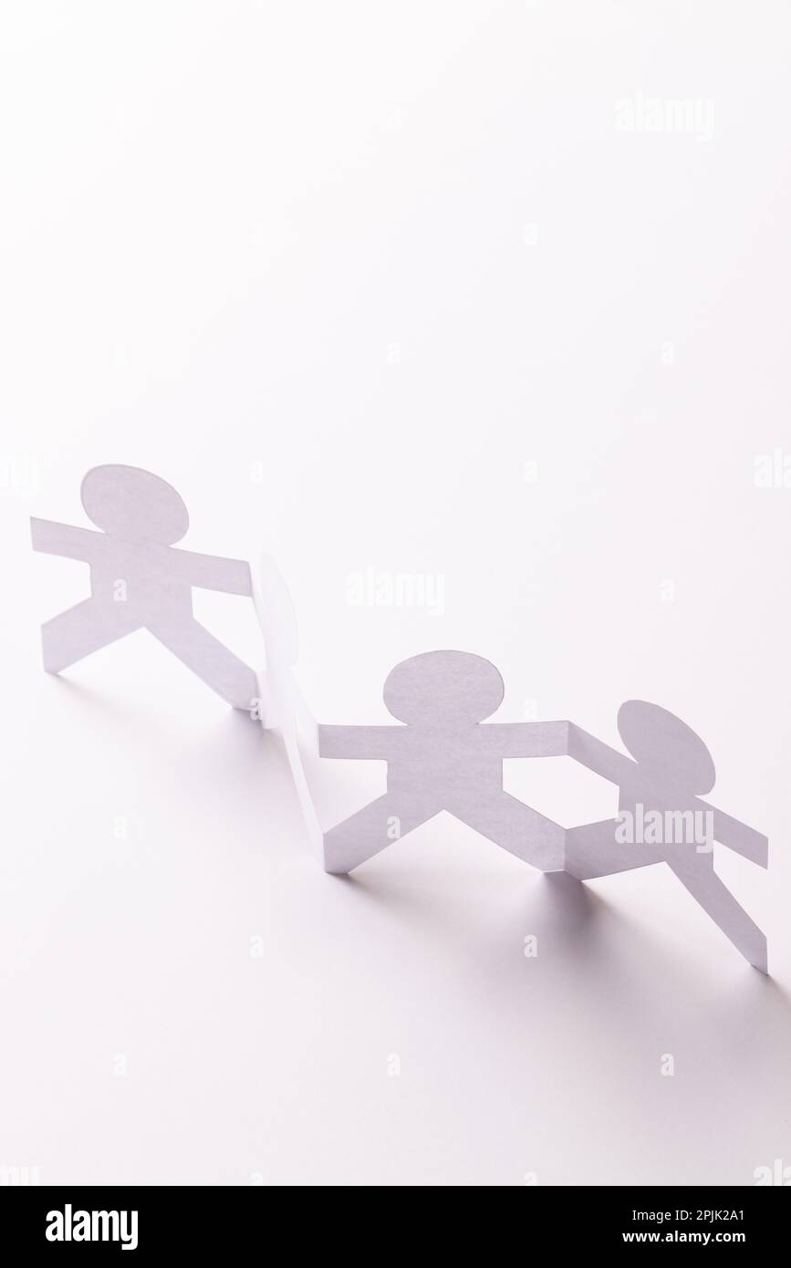 Close up of four paper cut out people figures holding hands with copy ...