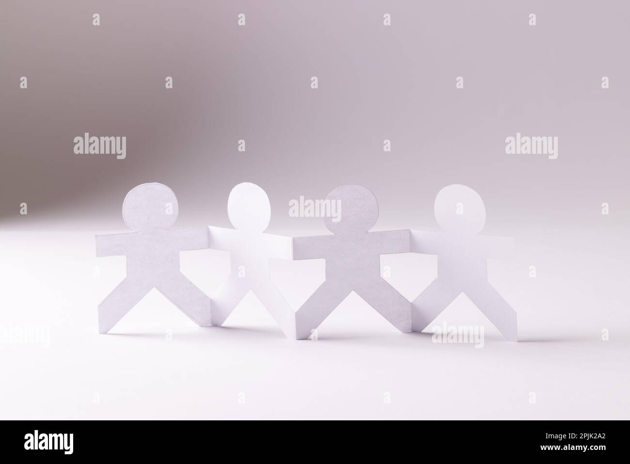 Close up of four paper cut out people figures holding hands with copy ...