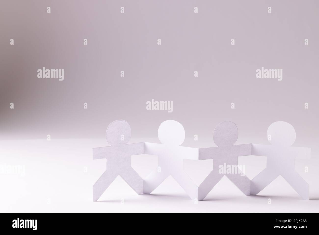 Close up of four paper cut out people figures holding hands with copy ...