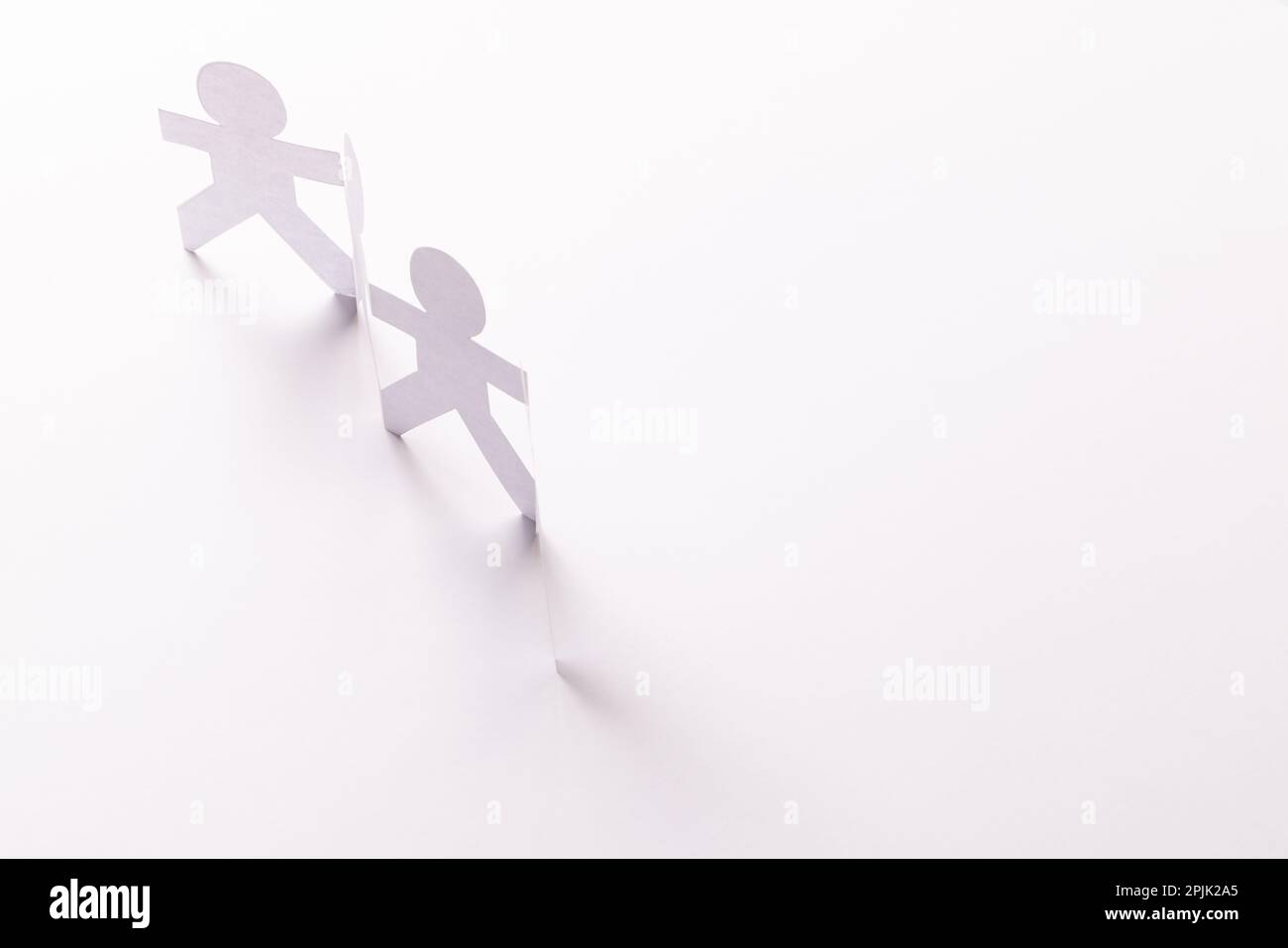 Close up of four paper cut out people figures holding hands with copy ...