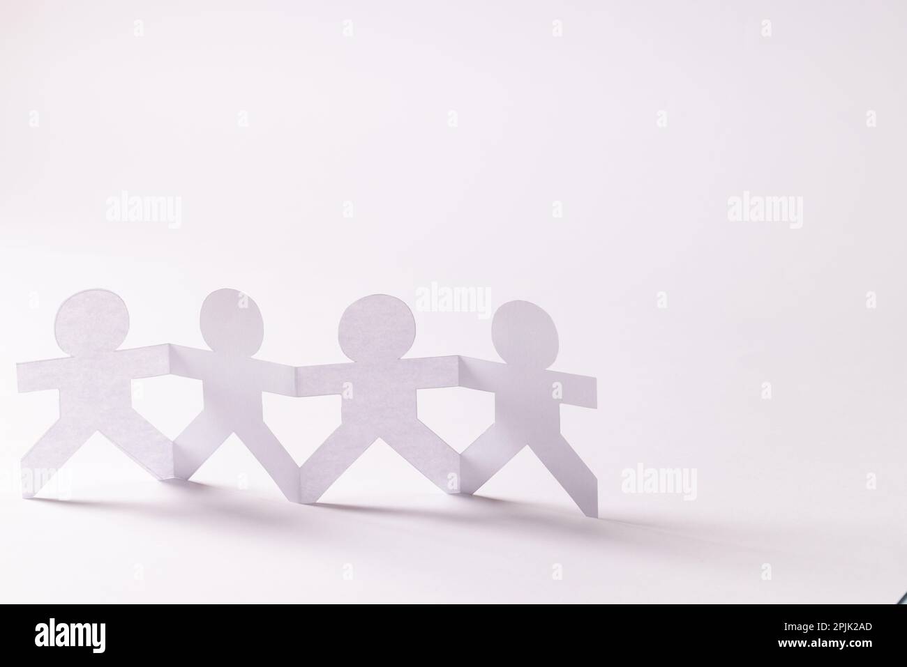 Close up of four paper cut out people figures holding hands with copy ...