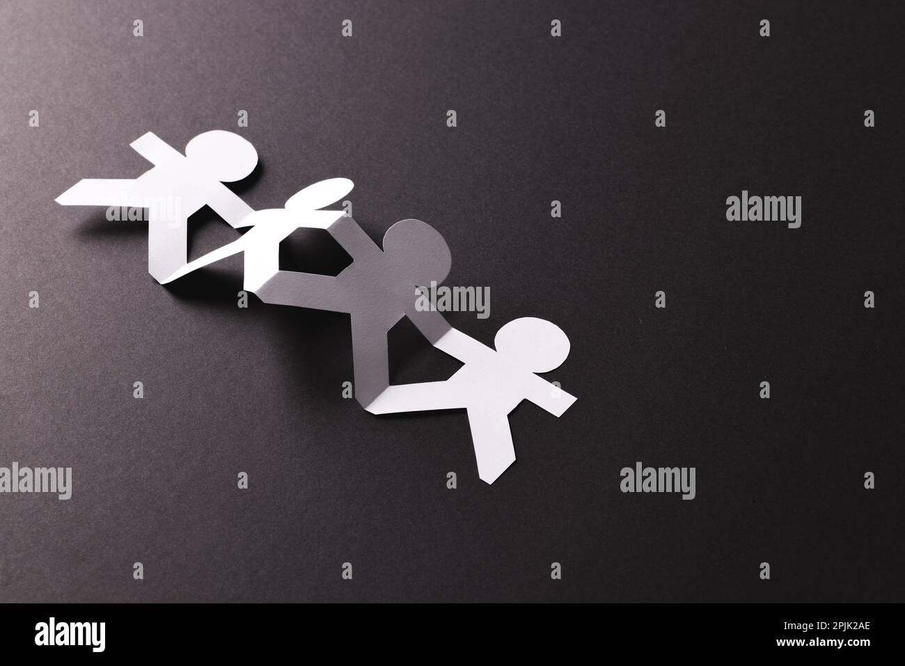 Close up of four paper cut out people figures holding hands with copy ...