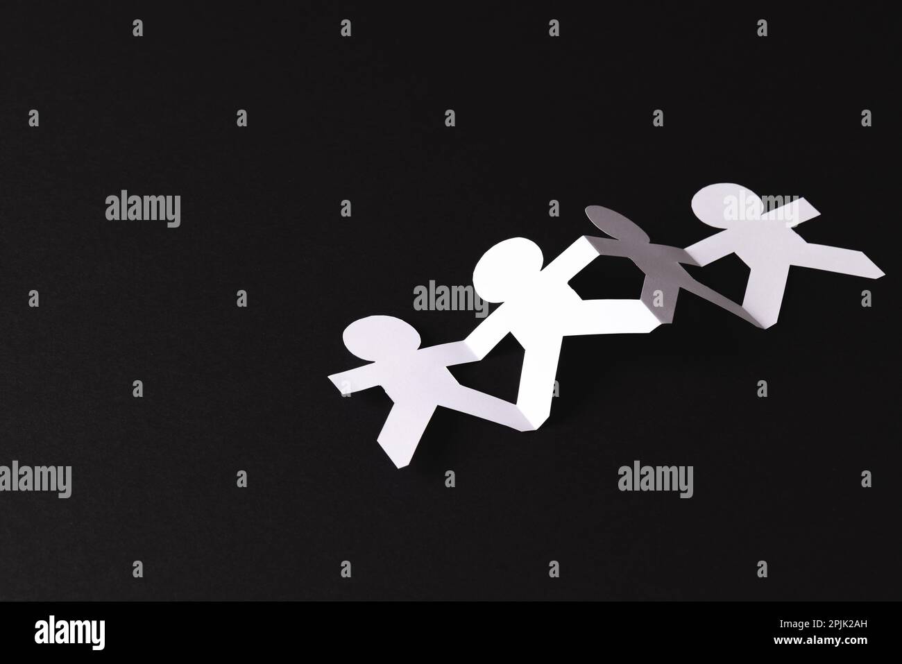 Close up of four paper cut out people figures holding hands with copy ...