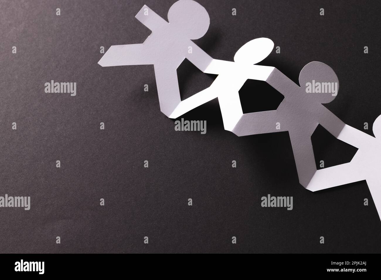Close up of four paper cut out people figures holding hands with copy ...