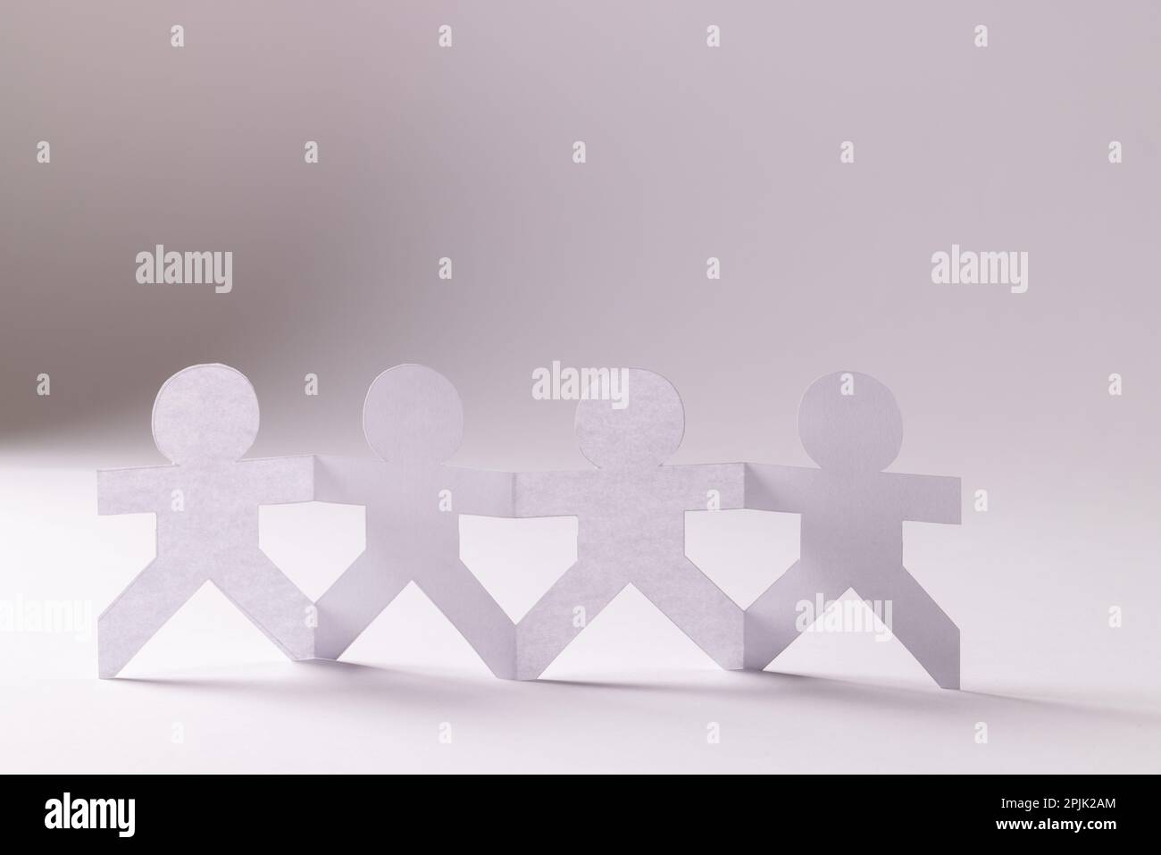 Close up of four paper cut out people figures holding hands with copy ...