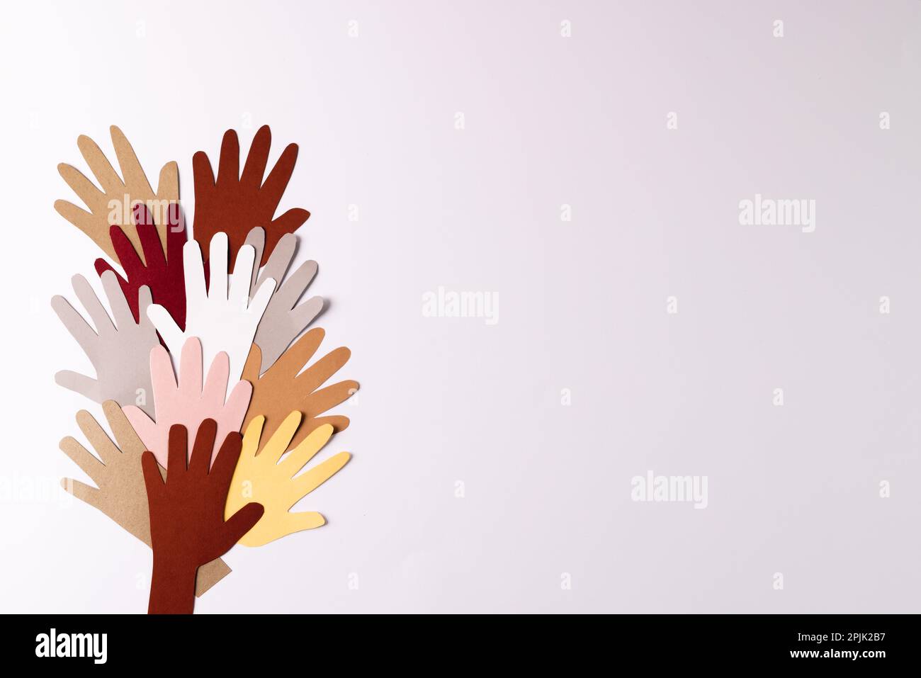 Paper cut out of multi coloured hands with copy space on white ...