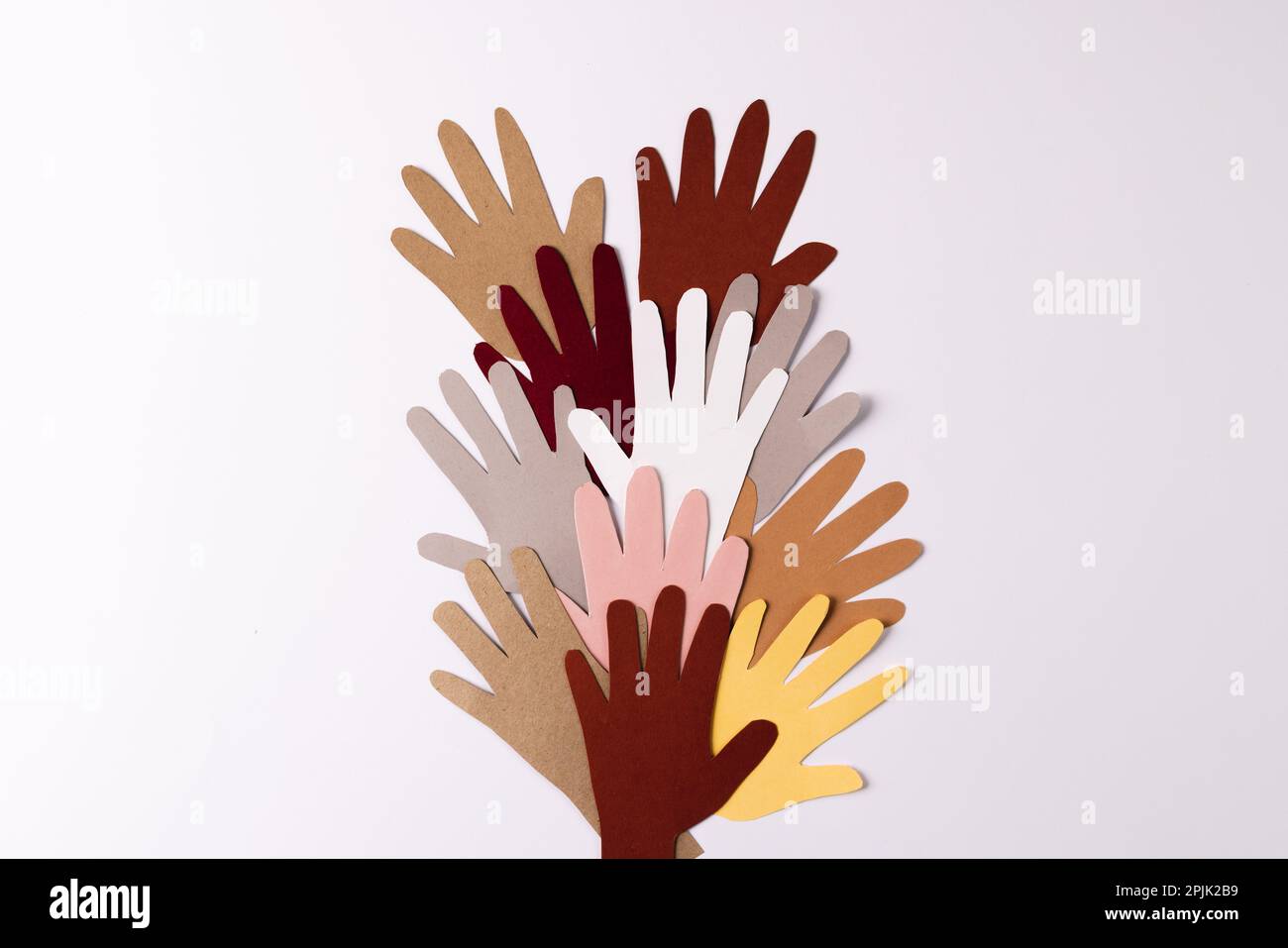 Paper cut out of multi coloured hands with copy space on white ...