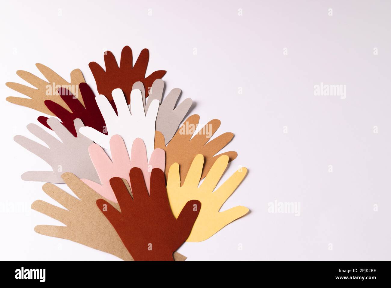 Paper cut out of multi coloured hands with copy space on white ...