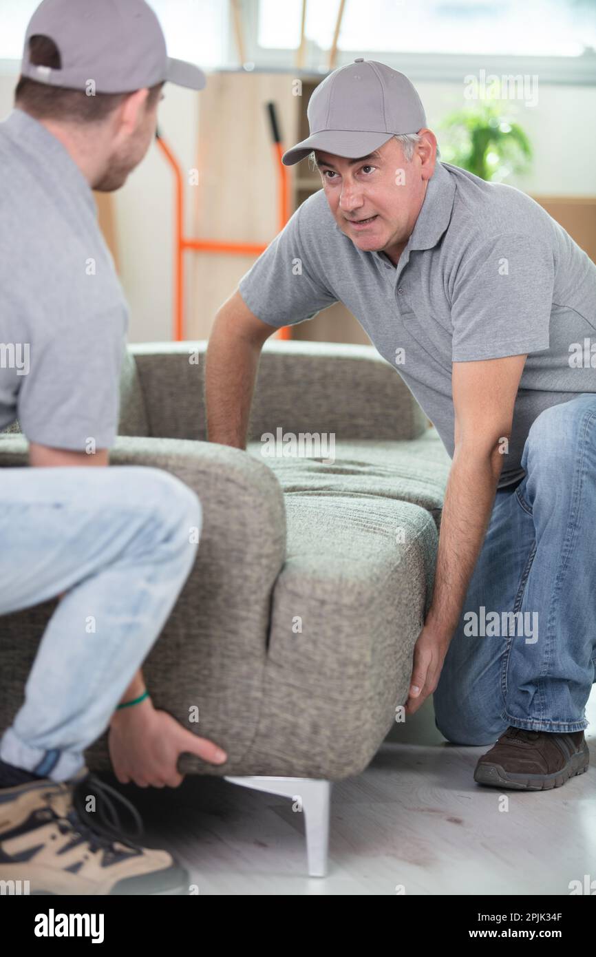 two men in uniform lifting a sofa Stock Photo - Alamy