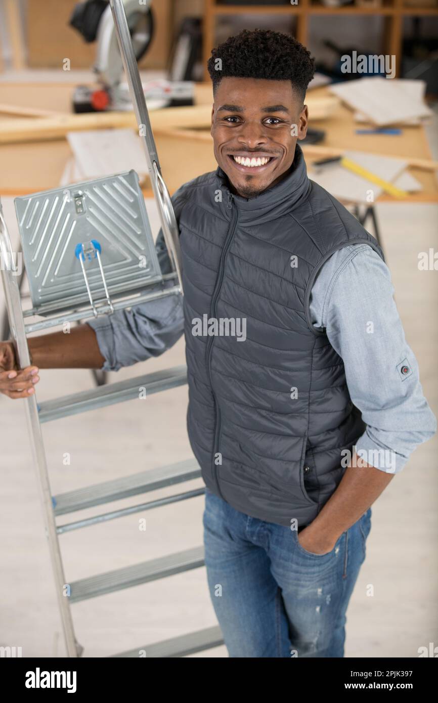 worker smiling holding ladder Stock Photo - Alamy