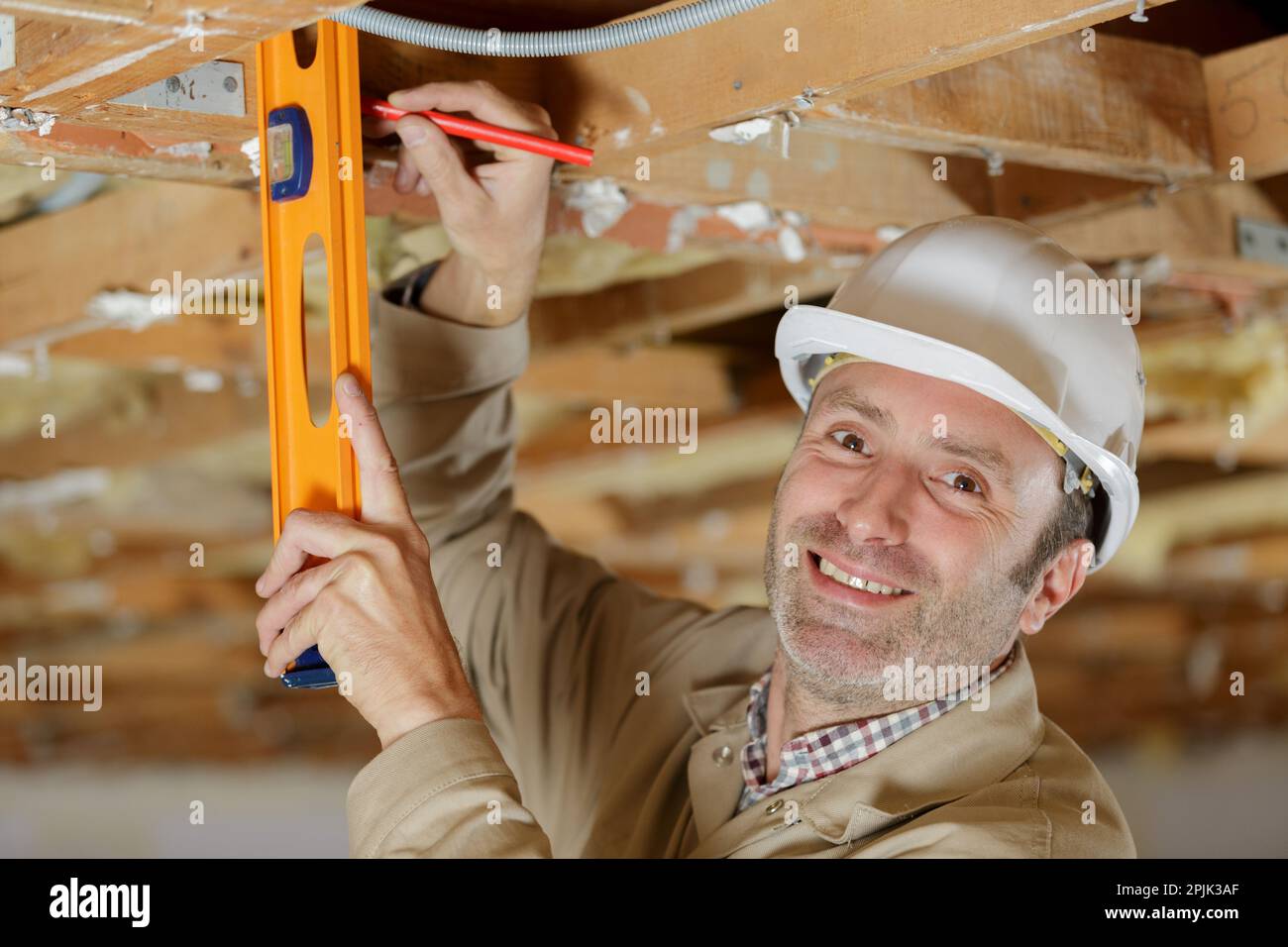 mature male builder using spirit level on ceiling joist Stock Photo - Alamy