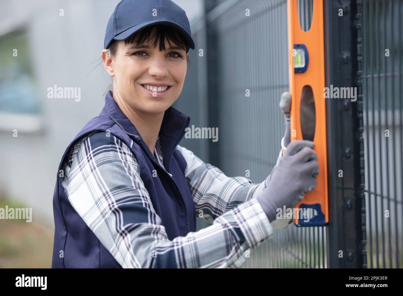 female worker checking fence with spirit level Stock Photo - Alamy