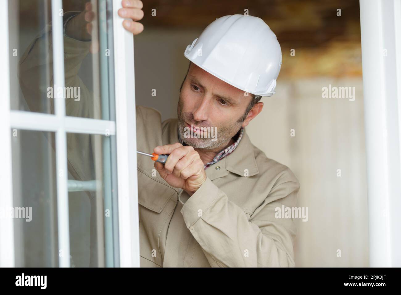 service man installing window with screwdriver Stock Photo - Alamy