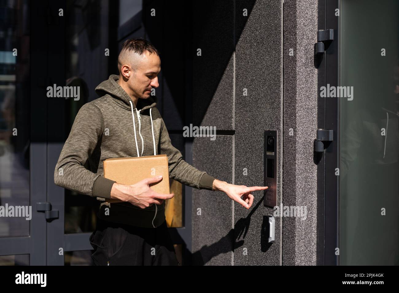 Happy man ringing intercom with camera in entryway Stock Photo - Alamy