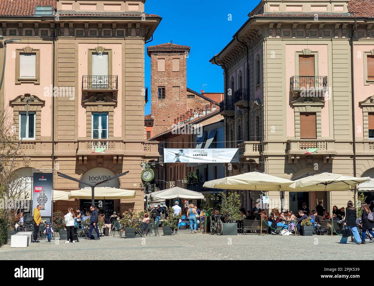 People on central town square as historic buildings and medieval tower ...