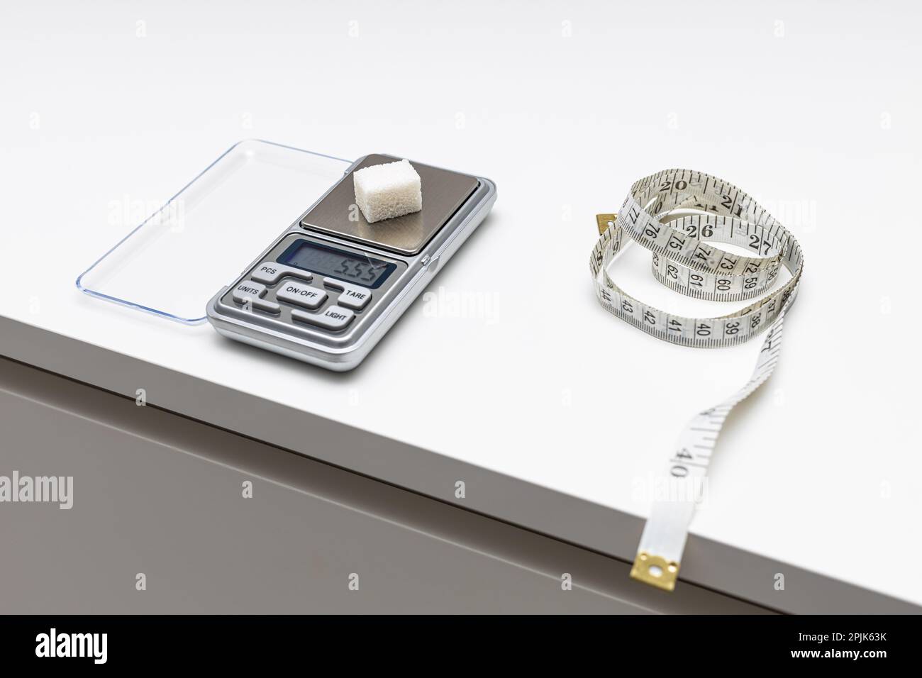 a sugar cube lies on a small scale Stock Photo - Alamy