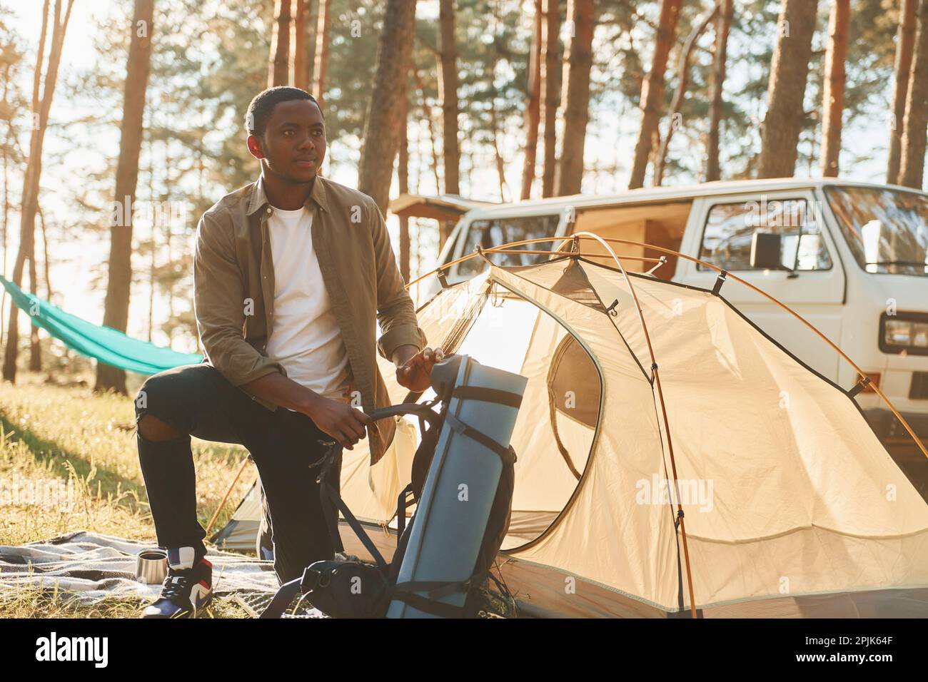 With mat near car. Man is traveling alone in the forest at daytime at ...