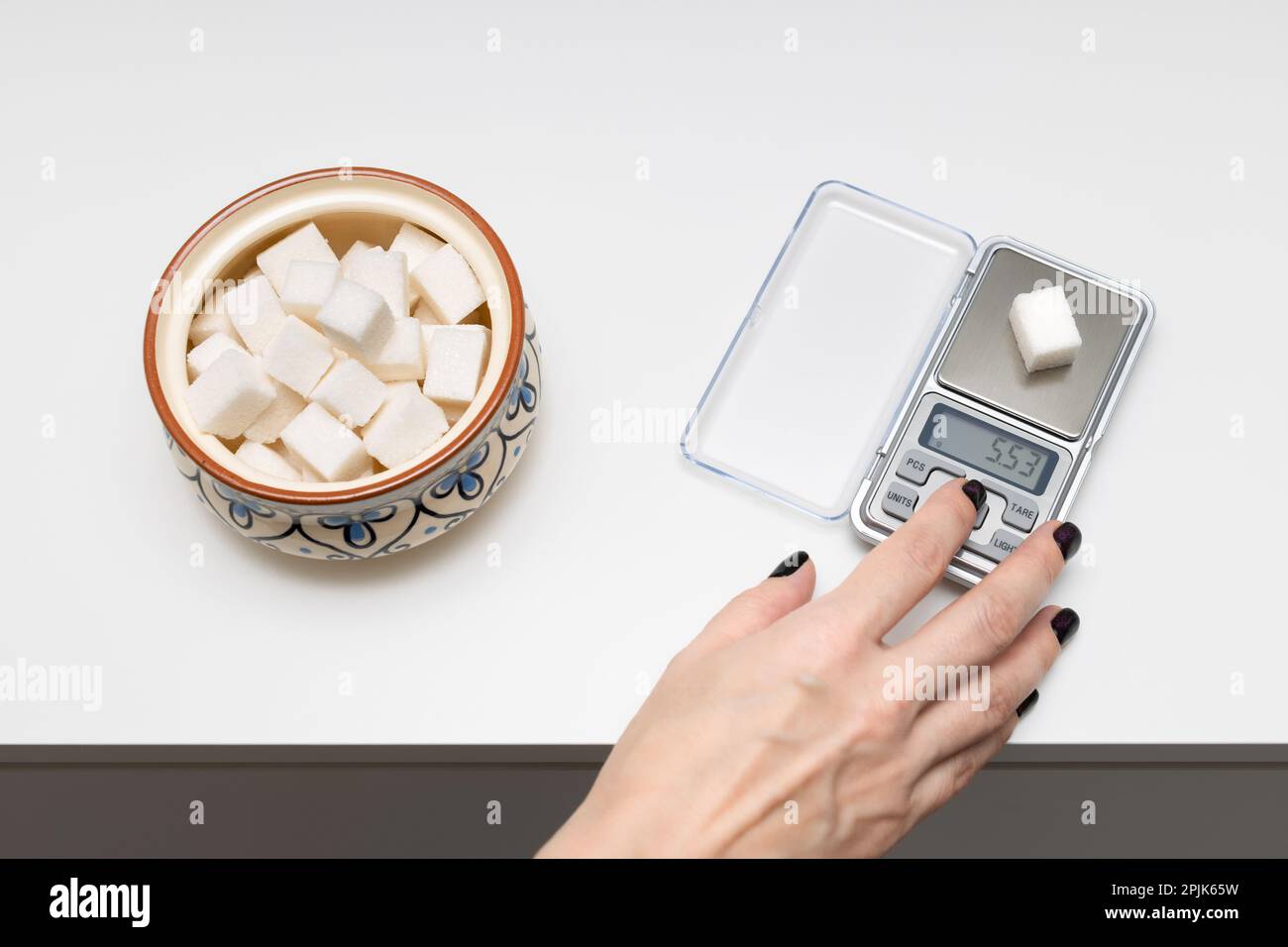 man weighing a cube of sugar on a small scale Stock Photo - Alamy