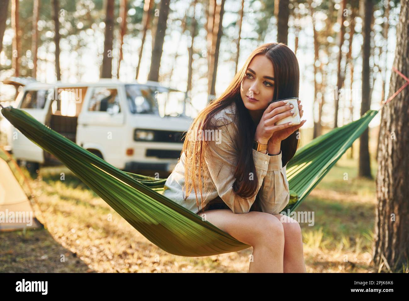 Sits on the hammock. Woman is traveling alone in the forest at daytime ...