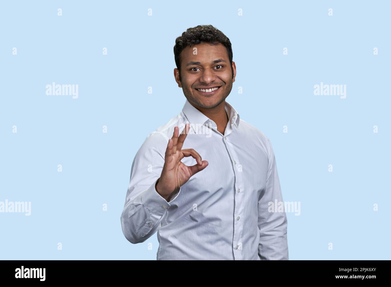 Happy indian young man shows the okay gesture sign. Isolated on pastel ...