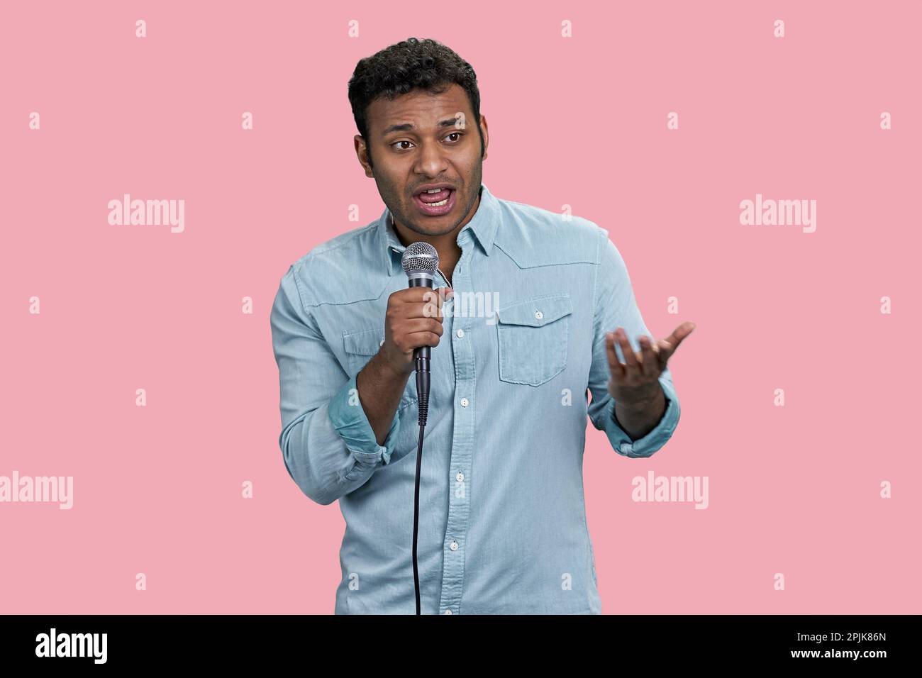 Portrait of a young handsome indian man with microphone. Isolated on ...