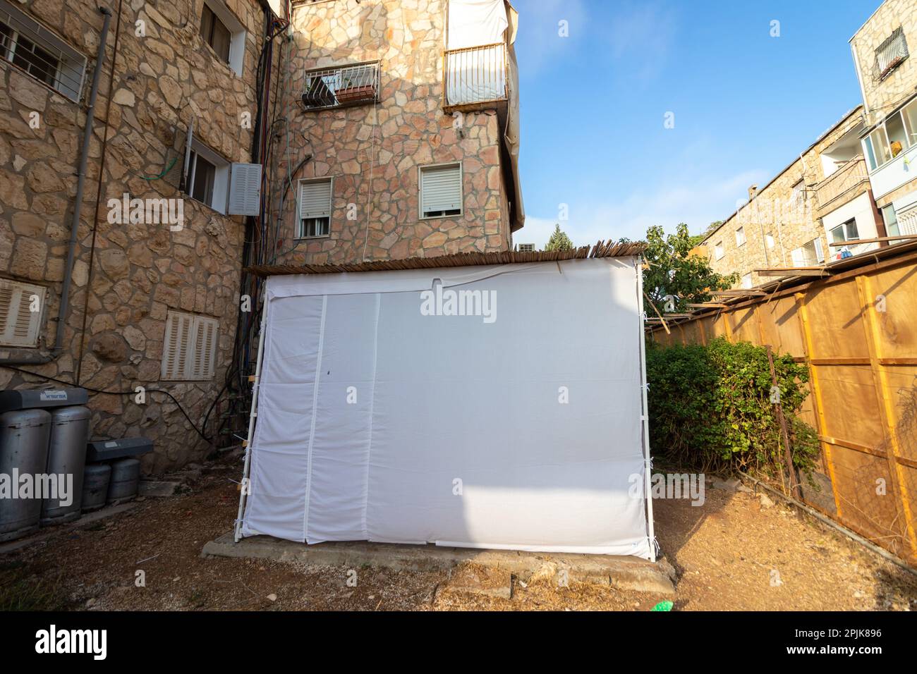 Sukkah covered with white cloth, built in the yard of a building in ...