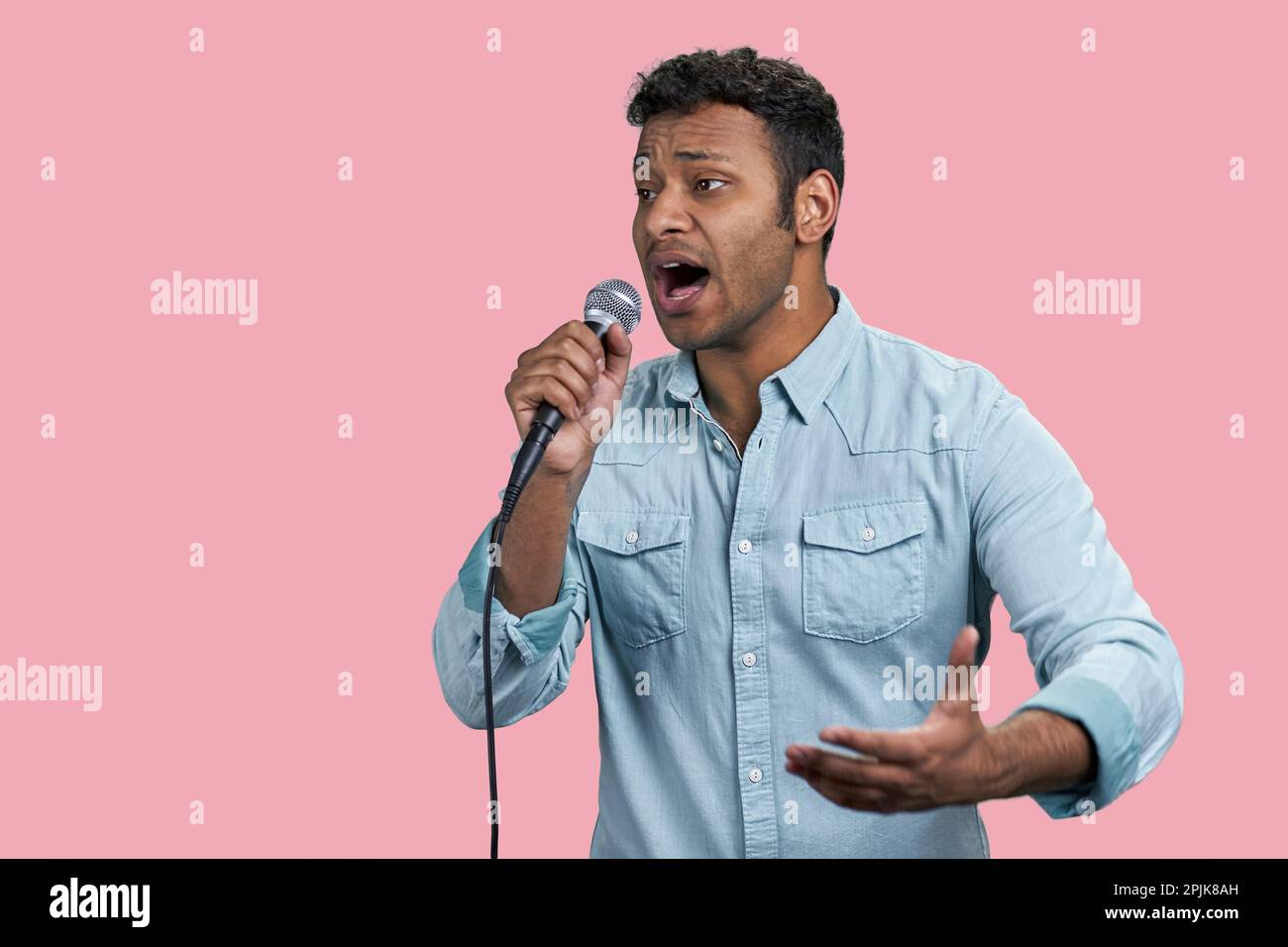Portrait of a young arab singer with microphone. Isolated on pink ...