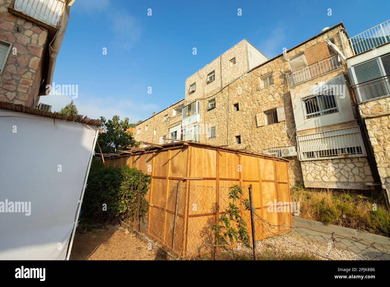 A wooden Sukkah in the yard of a building in Jerusalem, against a clear ...