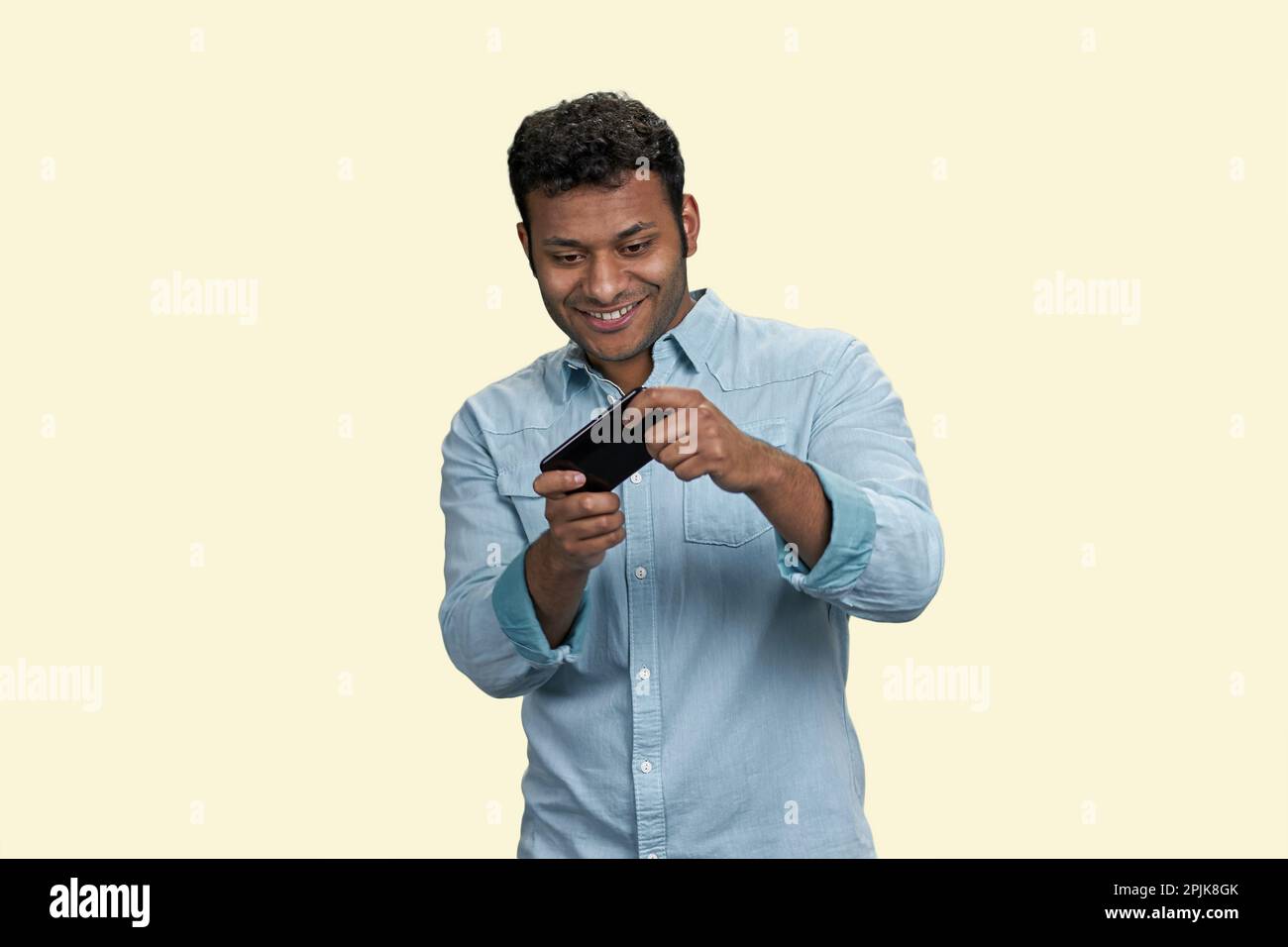 Excited happy young indian man gamer playing game in mobile videogame ...