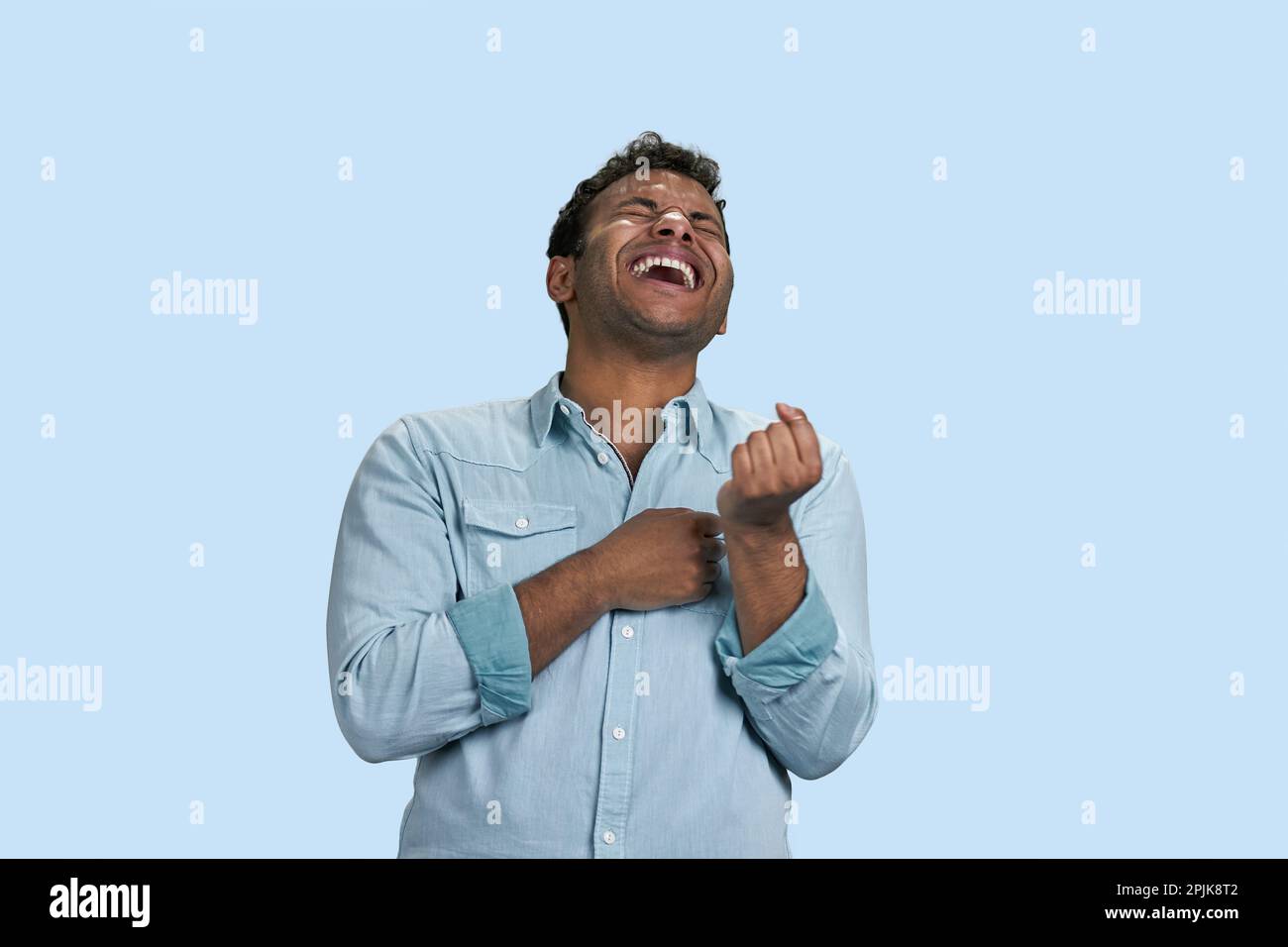 Young arab man is laughing out loud heartily. Isolated on pastel blue ...